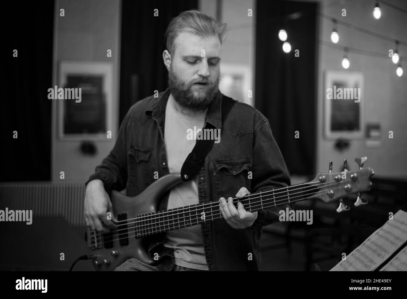 A young guy with a beard plays a bass guitar with five strings Stock ...
