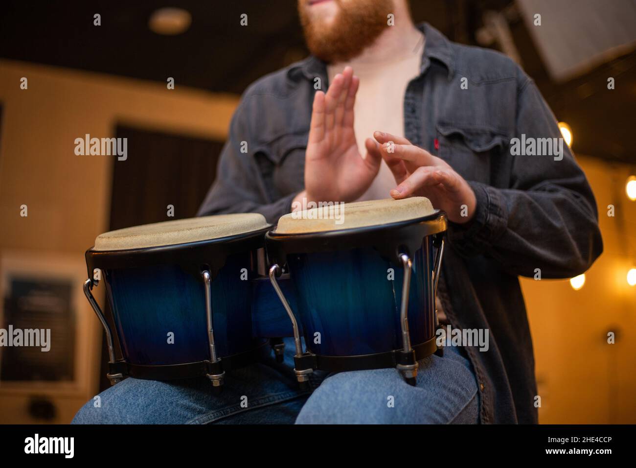 A young guy with a beard plays percussion bongos Stock Photo - Alamy