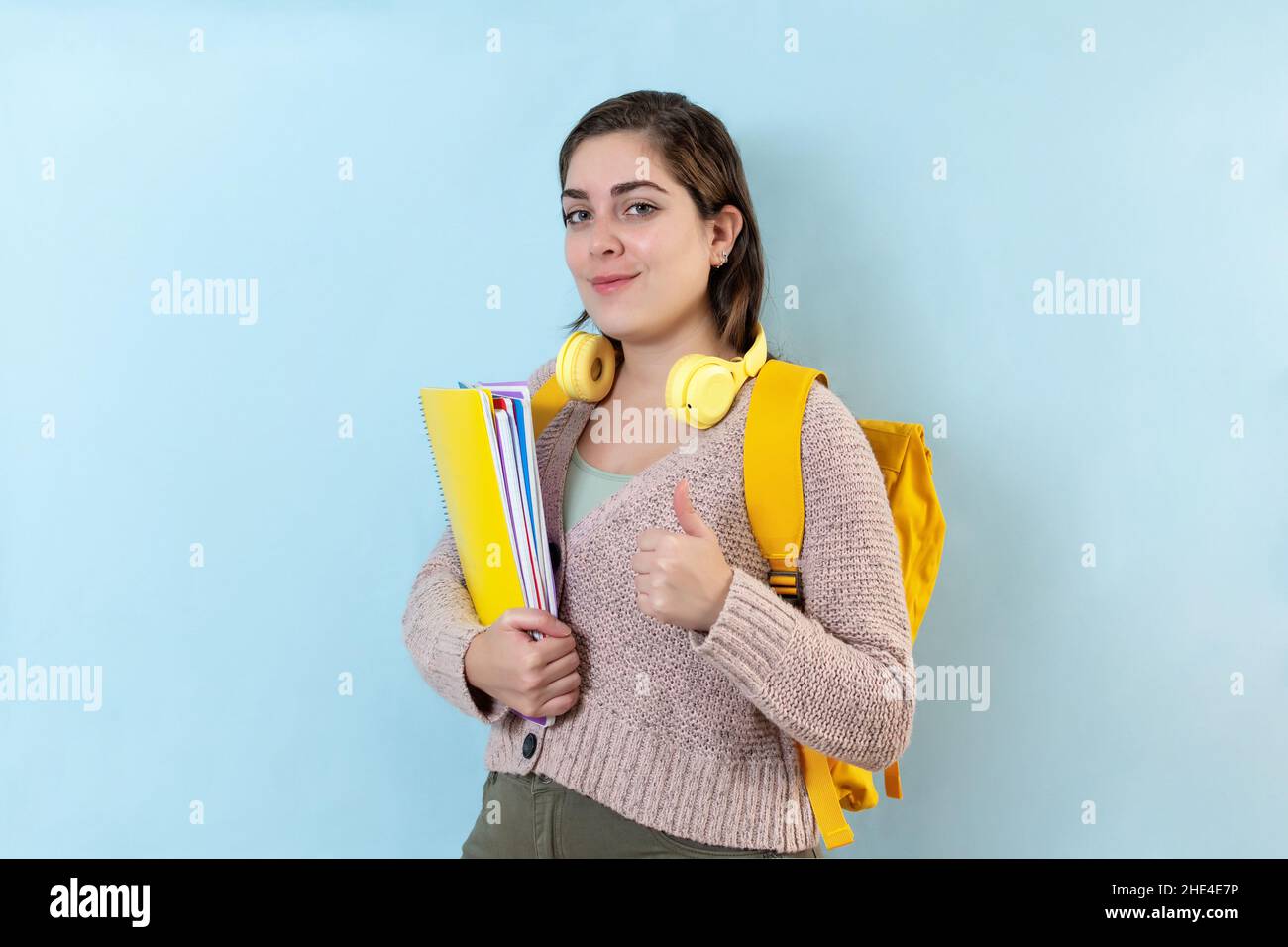 Satisfied girl student with yellow backpack, notebooks and headphones ...