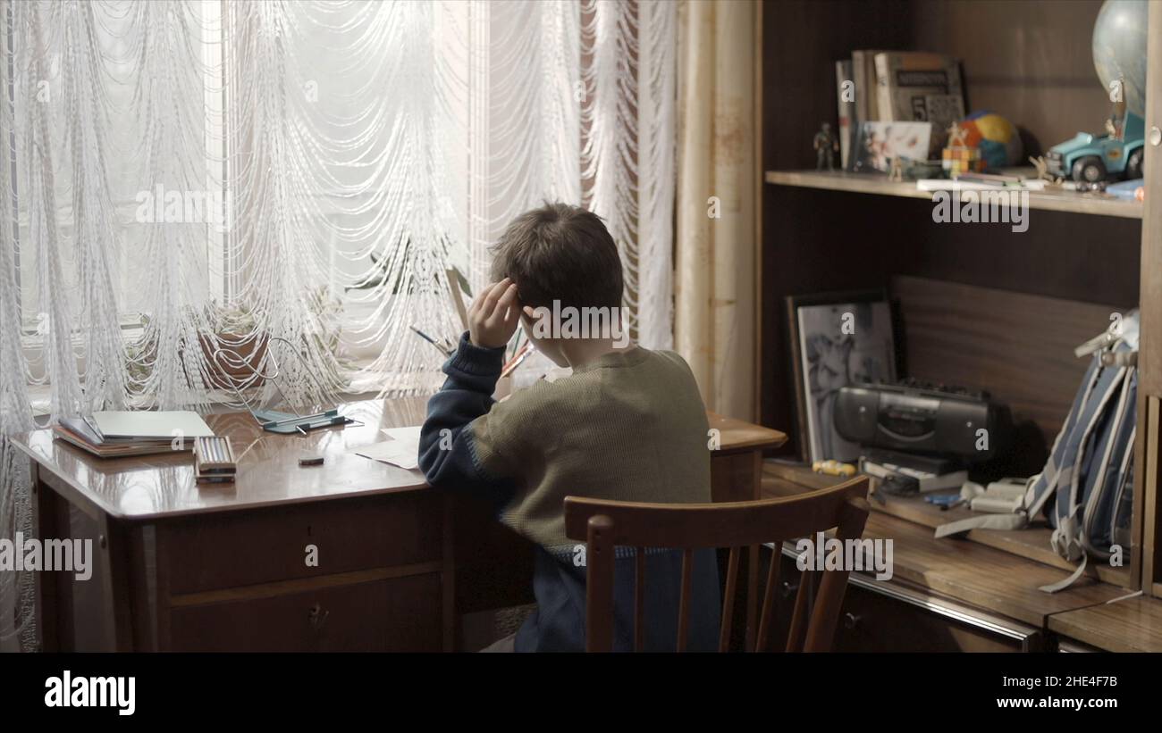 Rear view on guy doing homework. Thoughtful teen boy doing school ...