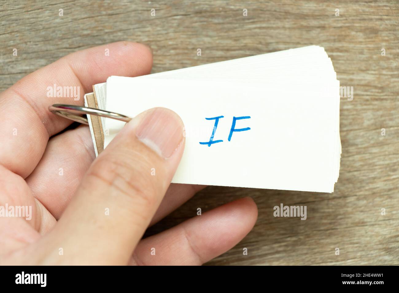 Man hold the flash card with handwriting word if on wood background ...