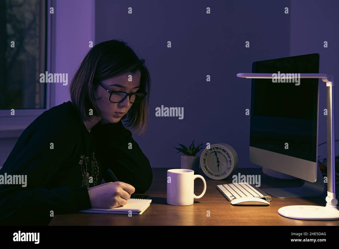 A young woman working at night in the workplace Stock Photo - Alamy