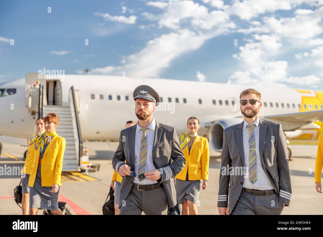 Male aviation captains and female flight attendants walking near ...