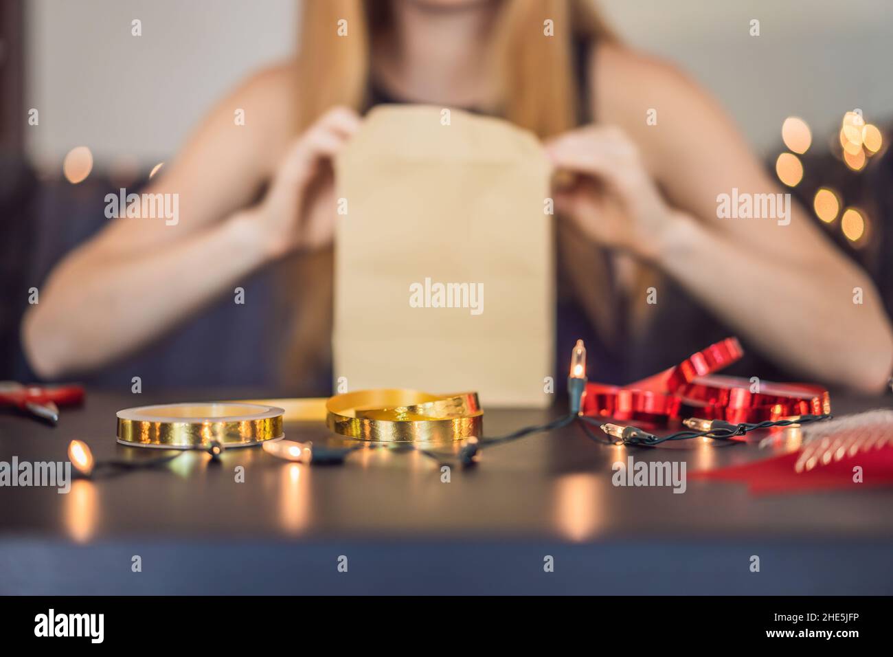 Young woman is packing presents. Present wrapped in craft paper with a ...
