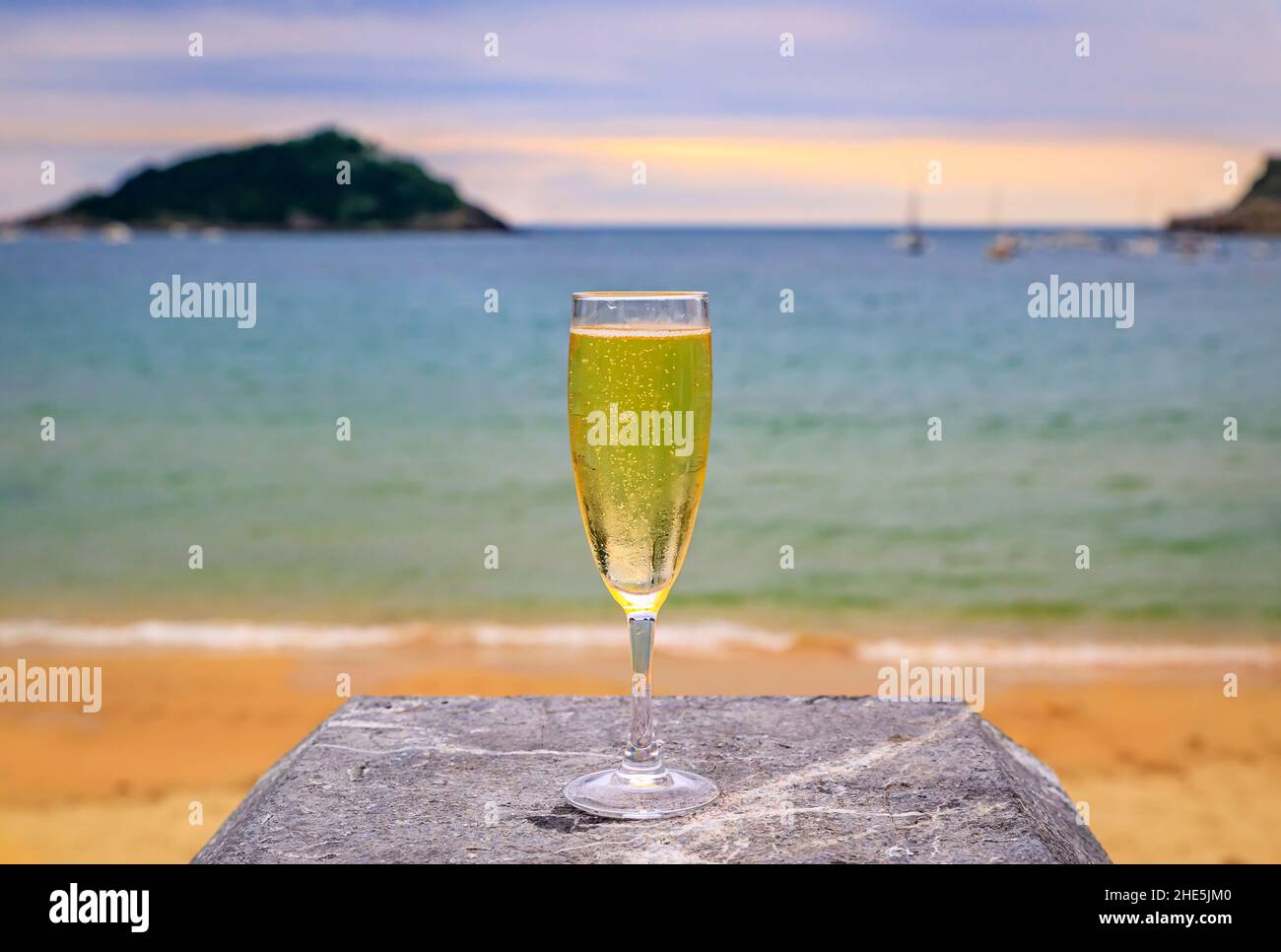 Glass of sparkling Spanish cava wine with a view of the beach and the ...