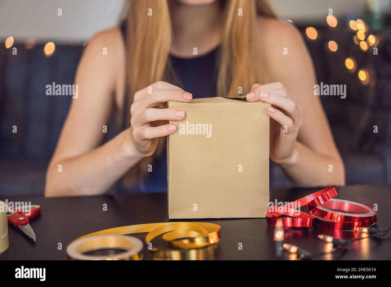 Young woman is packing presents. Present wrapped in craft paper with a ...