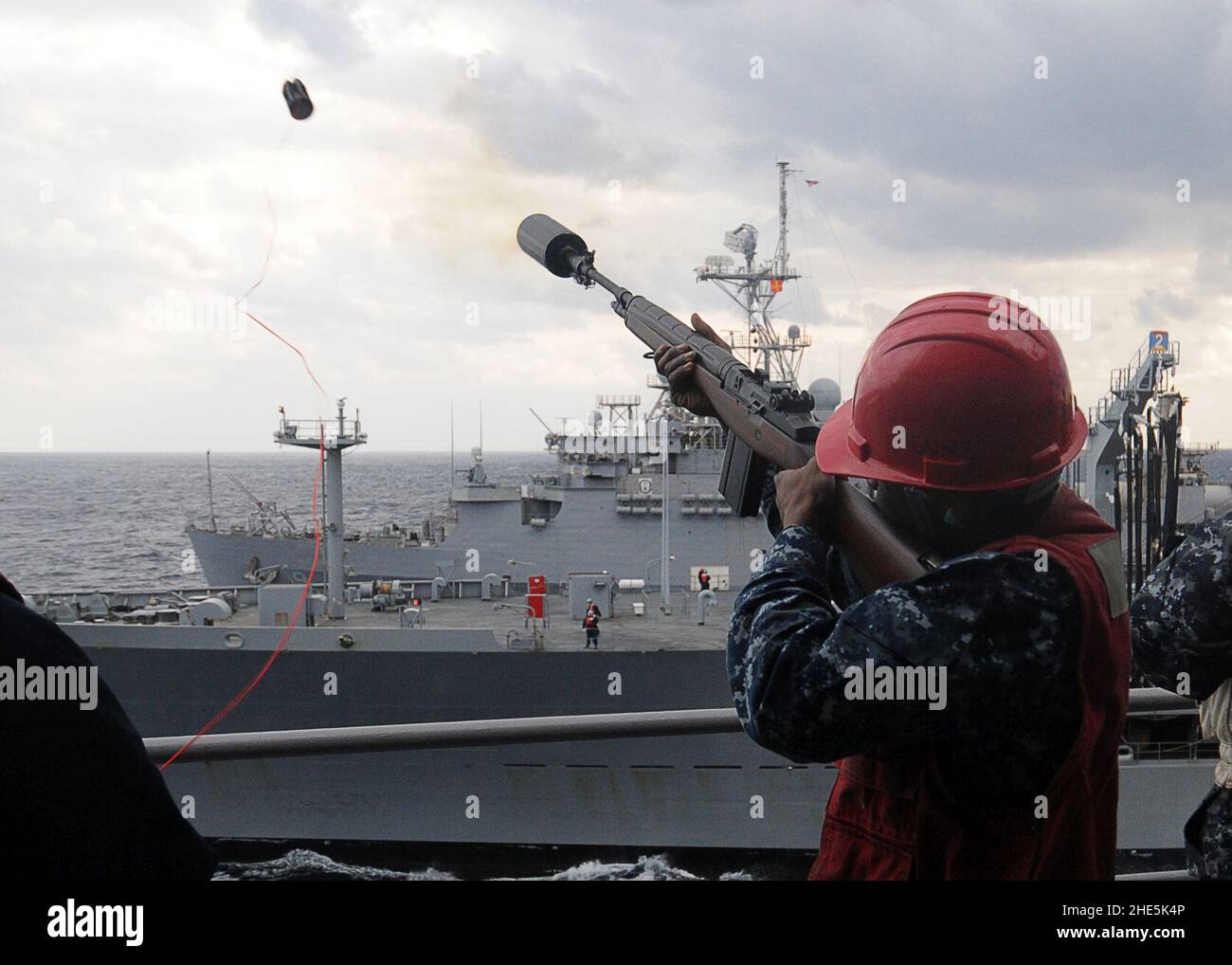 Sailor of USS Essex (LHD-2) firing shot line during underway ...