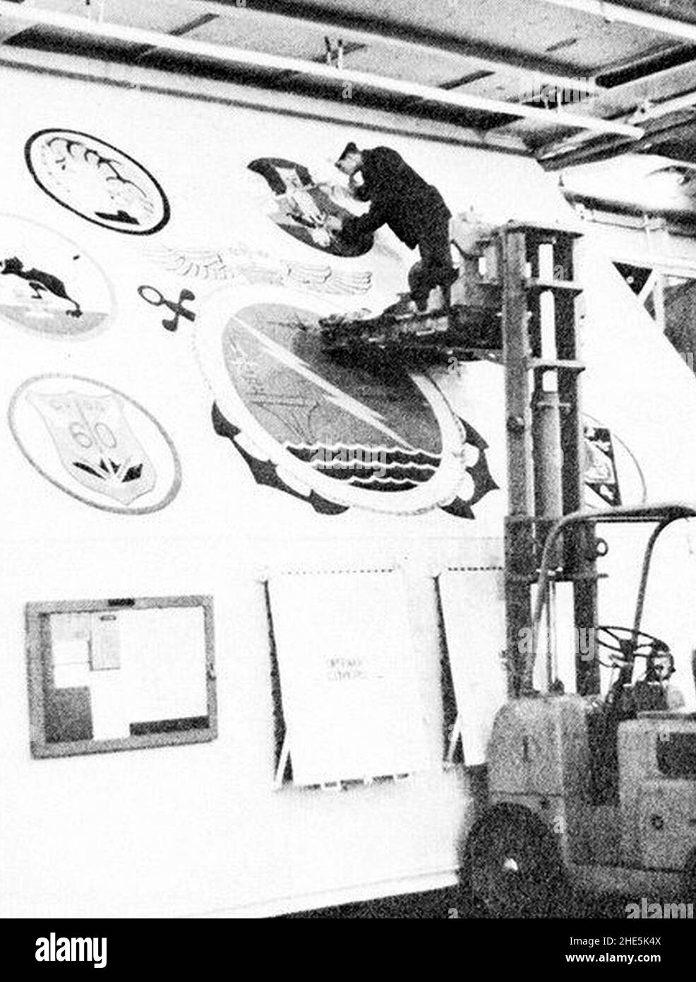 Sailor painting emblems in hangar of USS Randolph (CVS-15) in 1966 ...