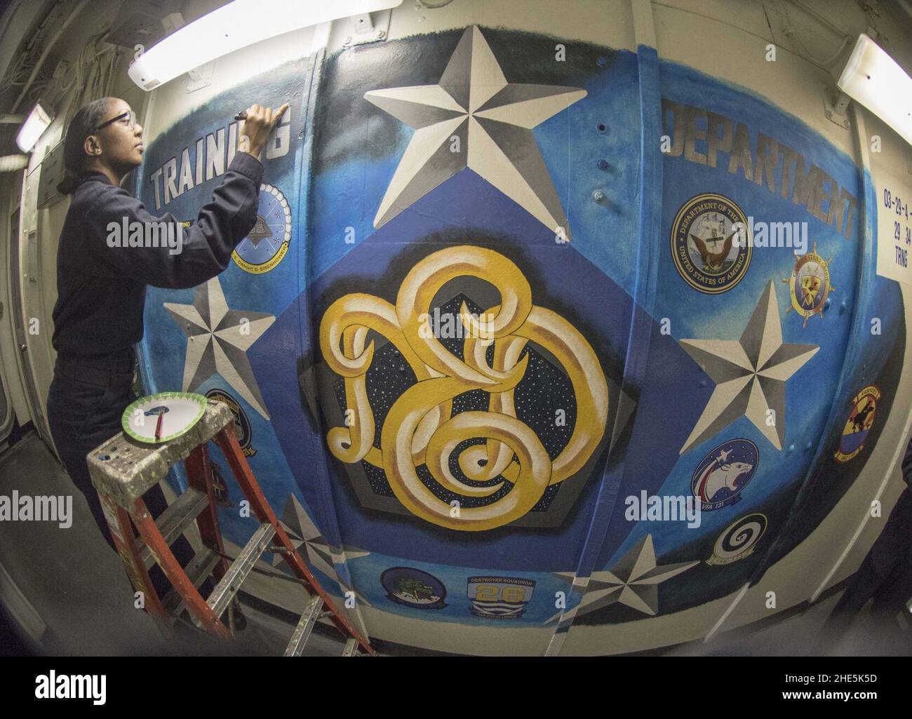 Sailor paints a mural for the training department aboard USS Dwight D ...