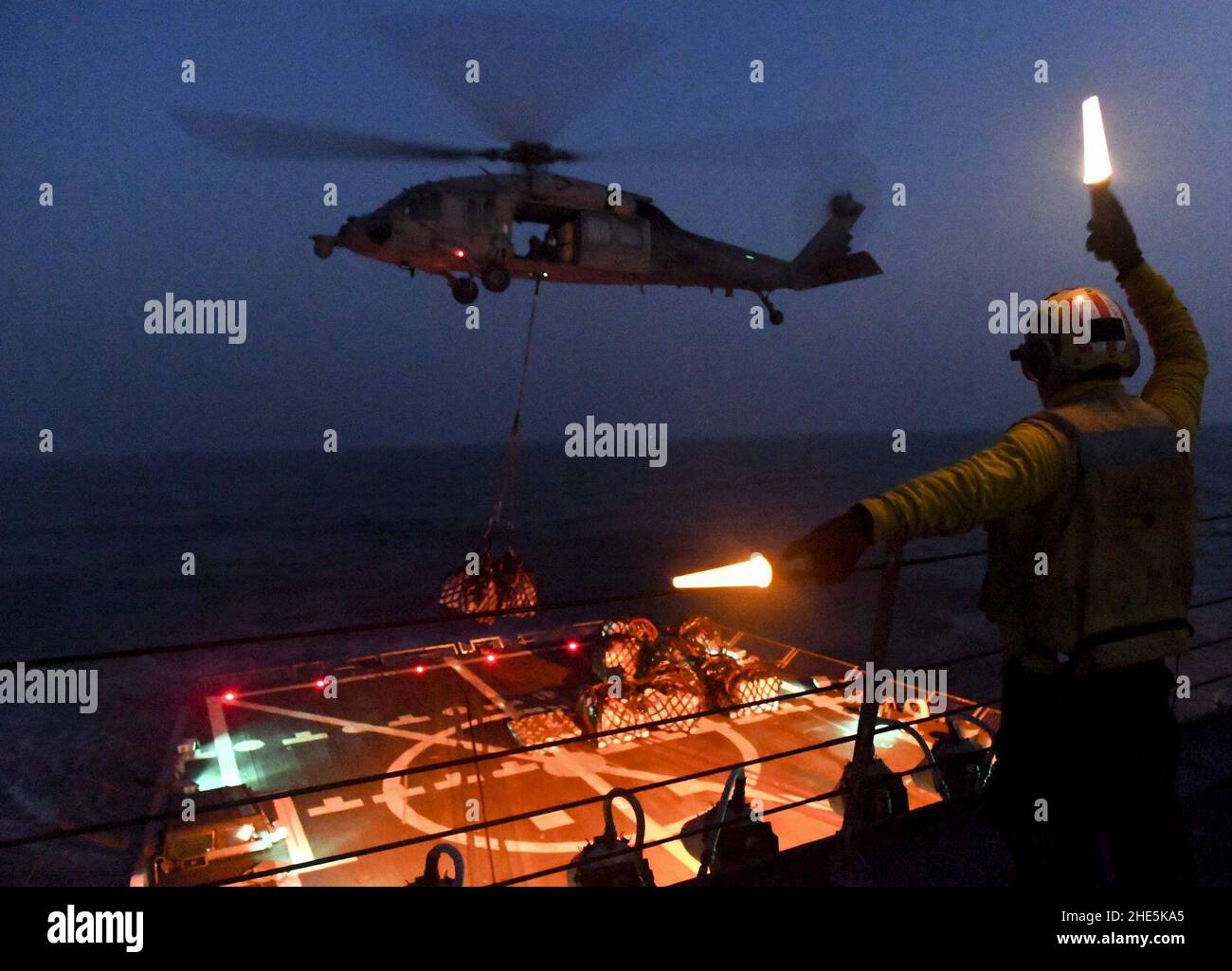 Sailor signals an MH-60S Sea Hawk helicopter during a replenishment-at ...
