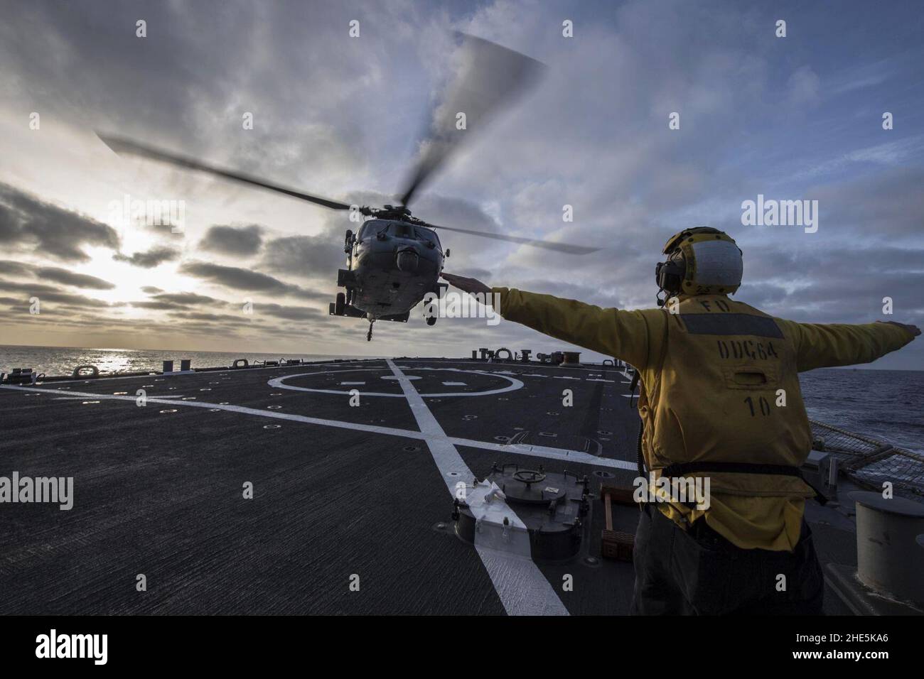 Sailor signals to an MH-60S Sea Hawk helicopter during flight quarters ...