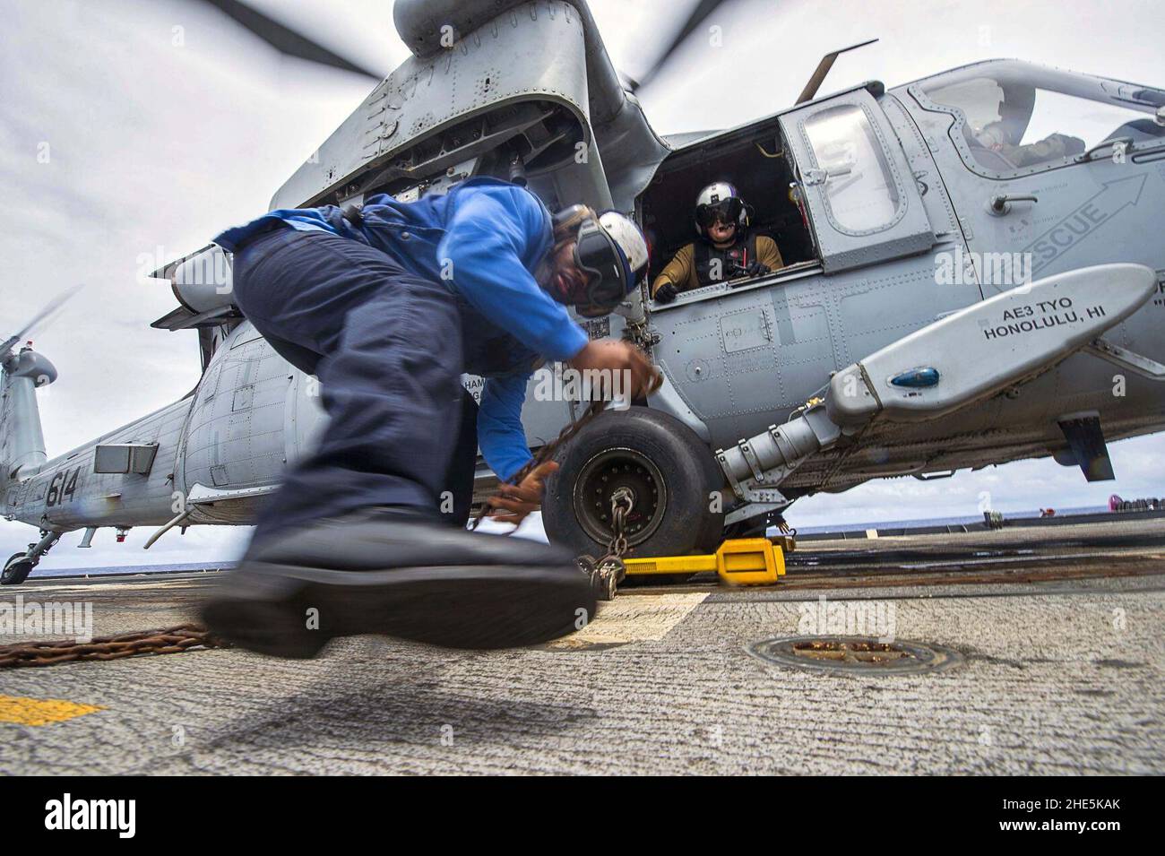 Sailor secures an MH-60s Sea Hawk helicopter with chocks and chains on ...