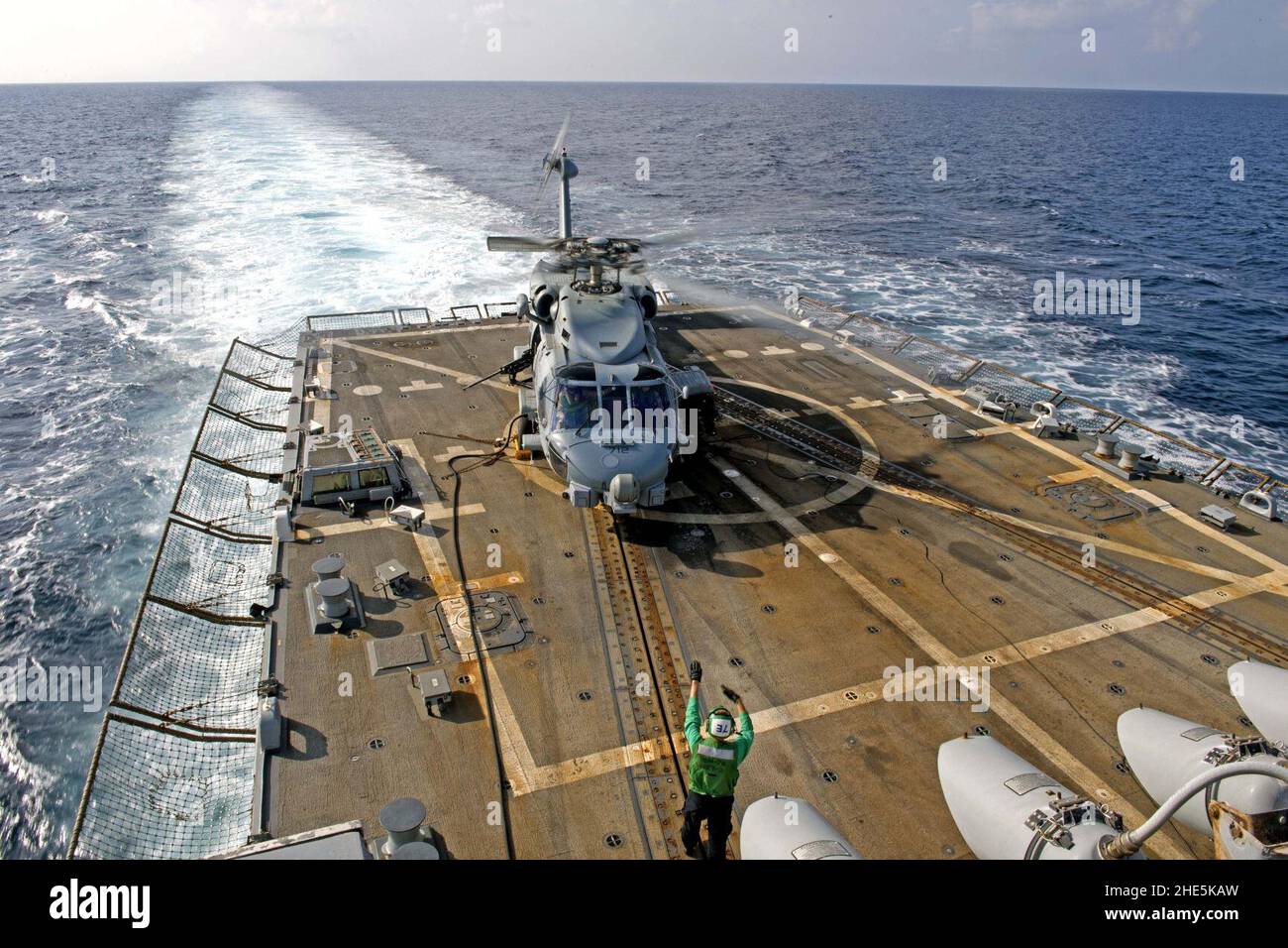 Sailor signals to the pilot of a MH-60R Sea Hawk helicopter after ...
