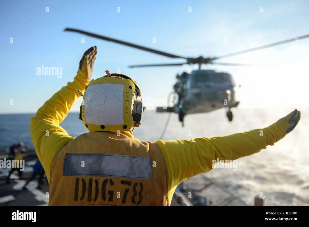 Sailor signals the pilot of an MH-60 Seahawk from the flight deck of ...