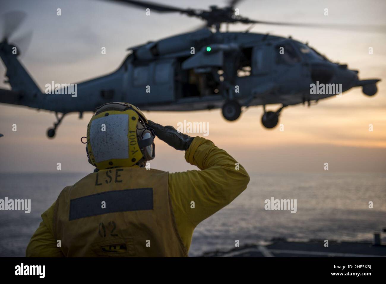 Sailor salutes an MH-60S Sea Hawk helicopter on the flight deck of USS ...