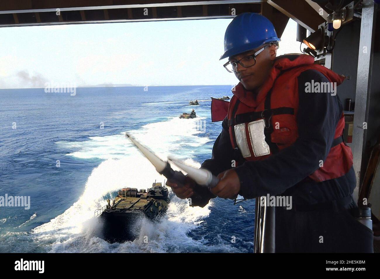 Sailor signals to an amphibious assault vehicle enters the water from ...