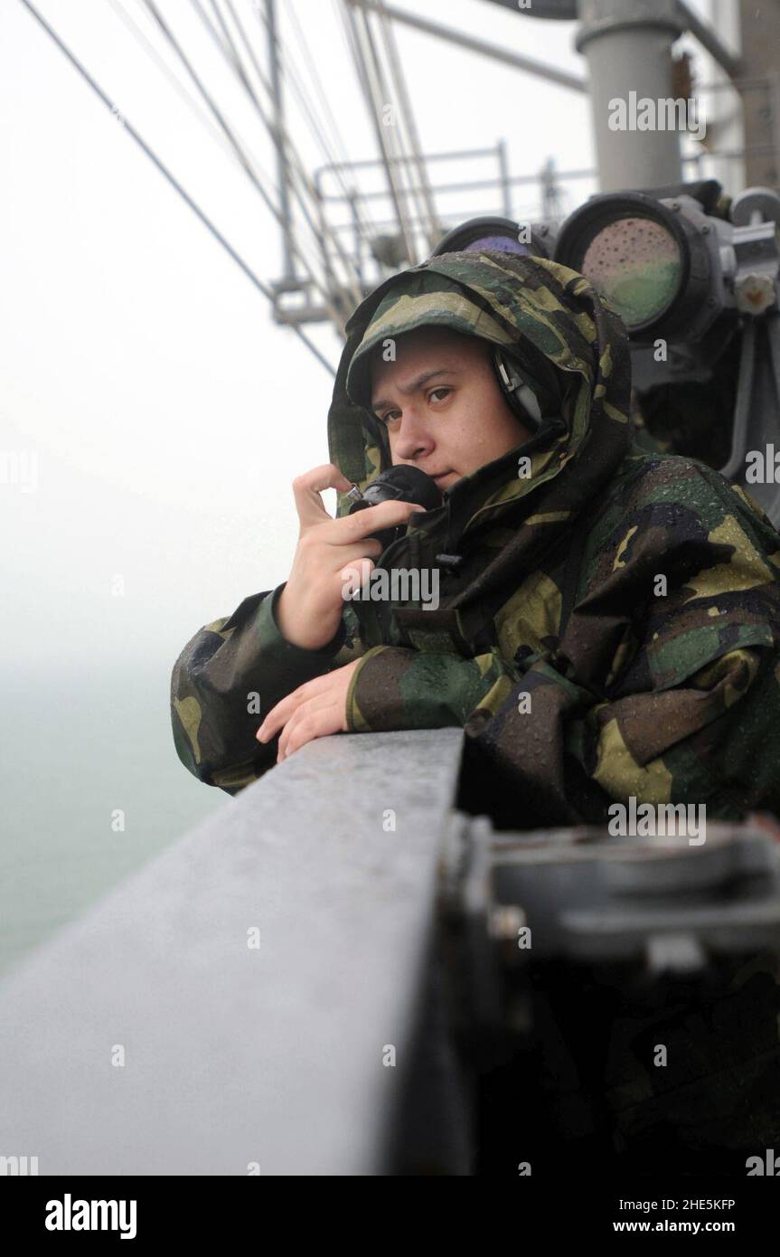 Sailor watches carrier pull into port Stock Photo - Alamy