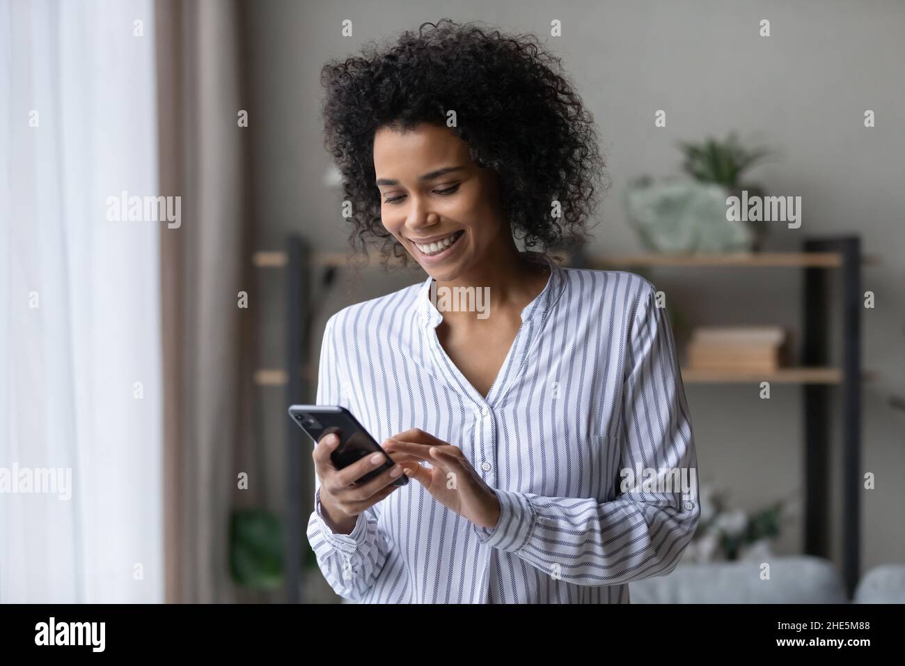Smiling young african woman using smartphone applications Stock Photo ...