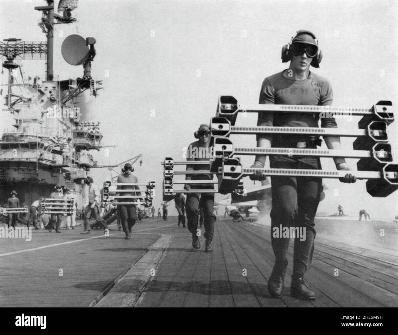 Sailors carrying wheel chocks across the flight deck of carrier USS ...
