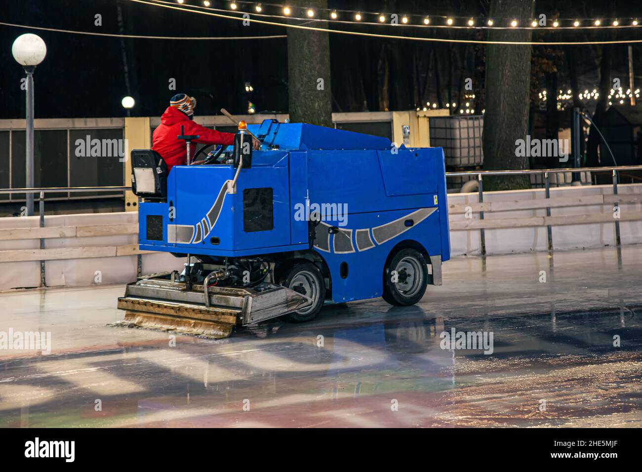 A stadium worker cleans an ice rink on a blue modern ice cleaning ...
