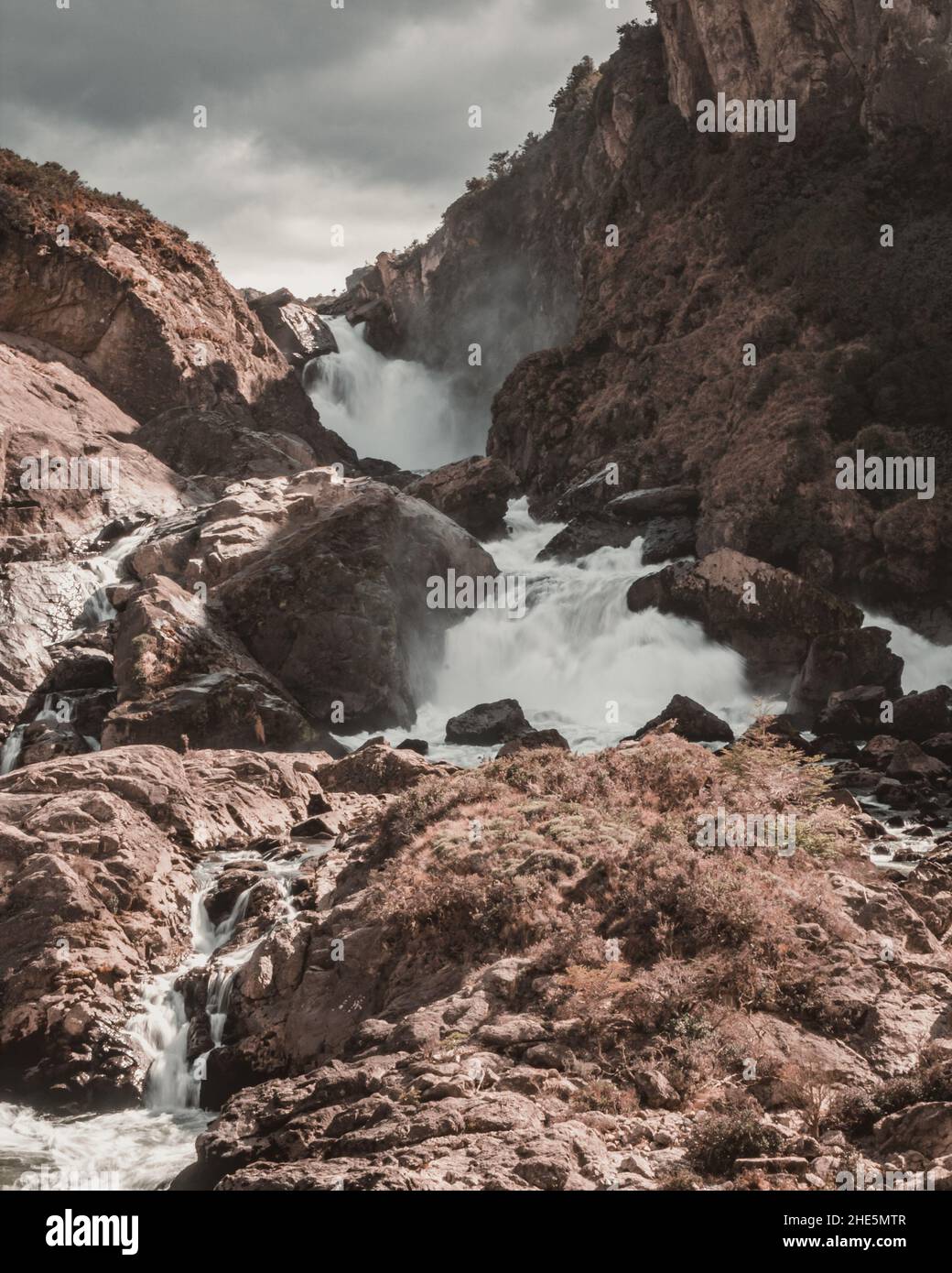 Photo of a waterfall hitting rocks and a cloudy sky Stock Photo - Alamy