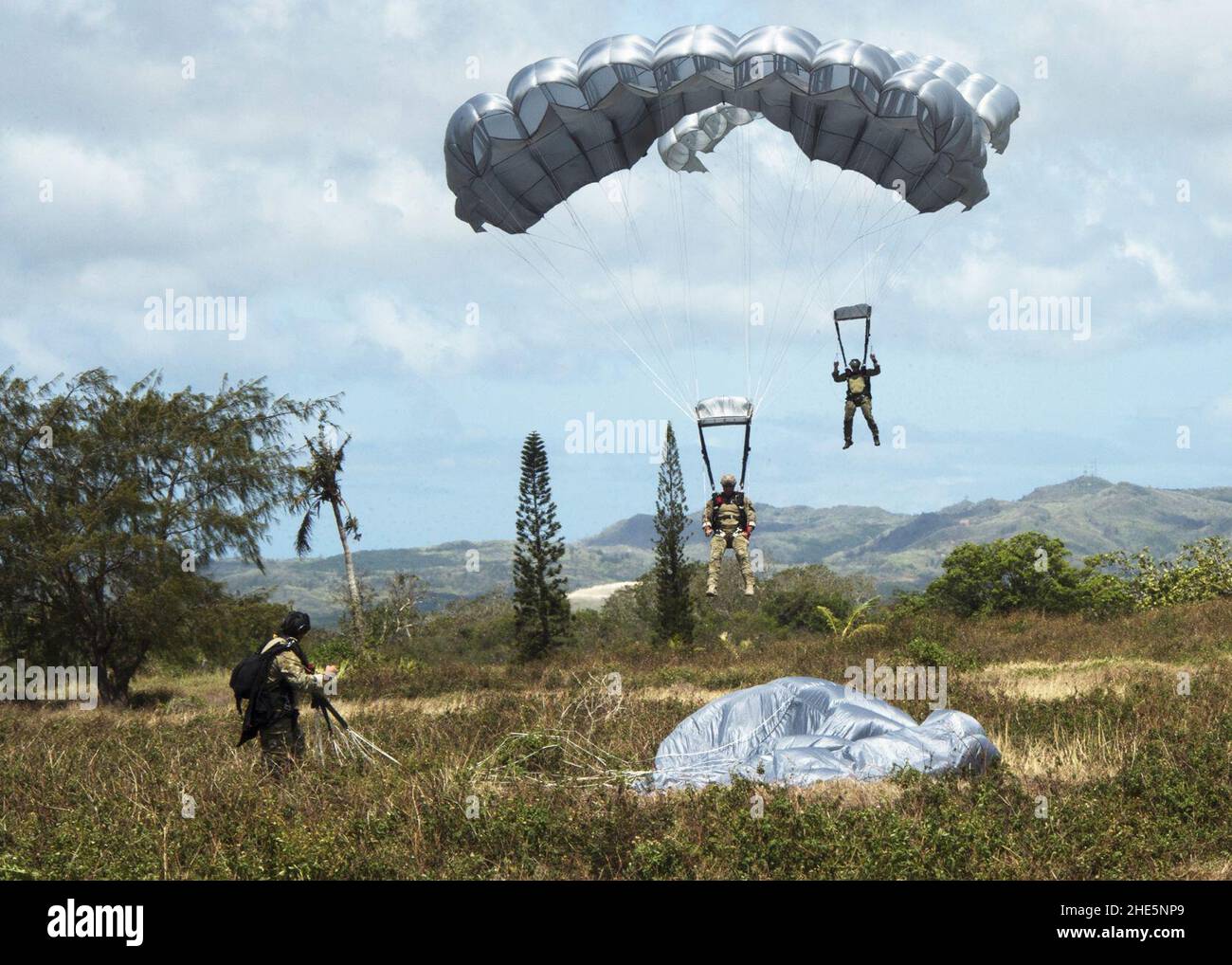 Sailors land and retrieve their parachutes in Guam after a high ...