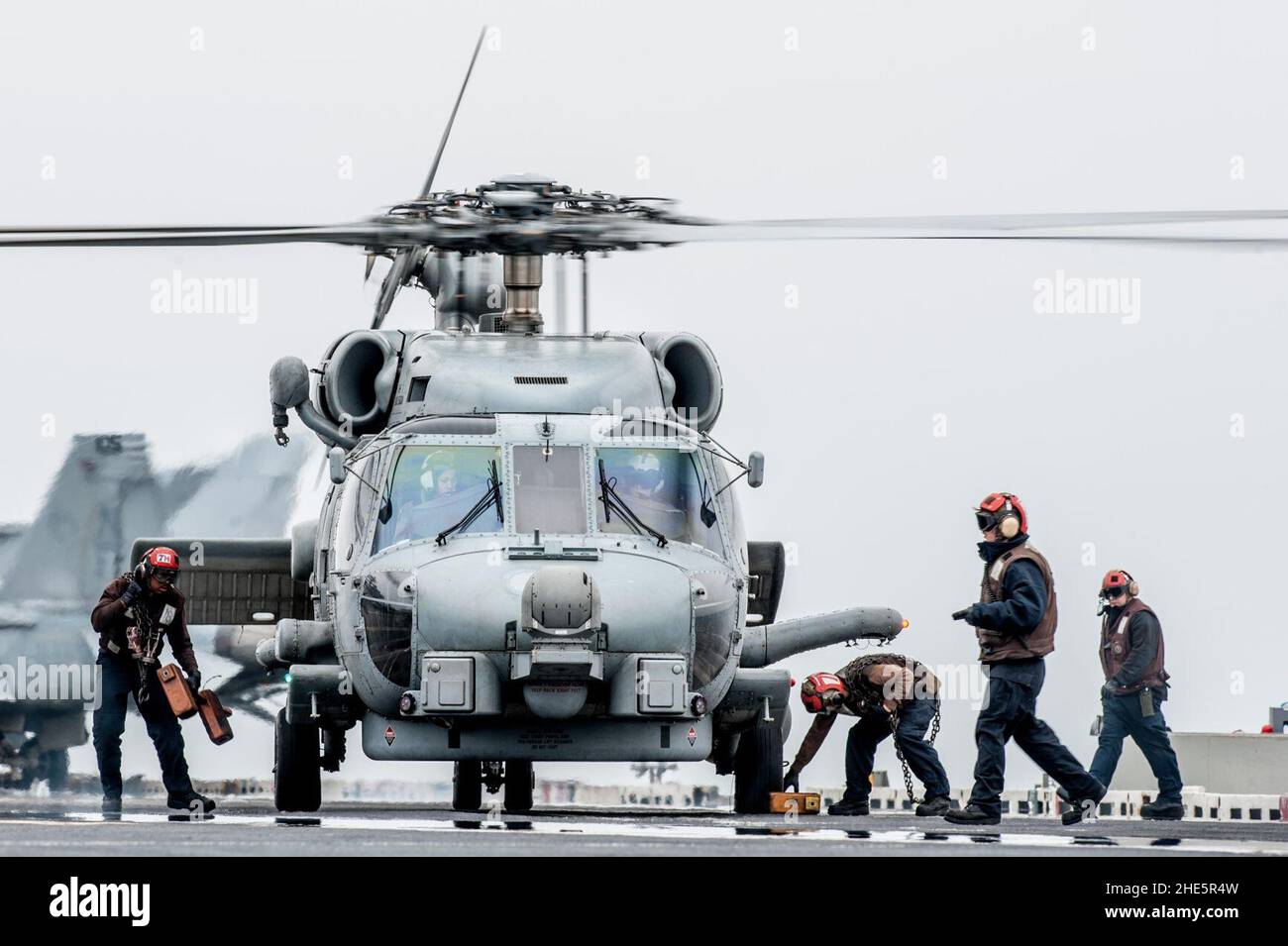 Sailors remove tire chocks from the landing gear of an MH-60R Sea Hawk ...