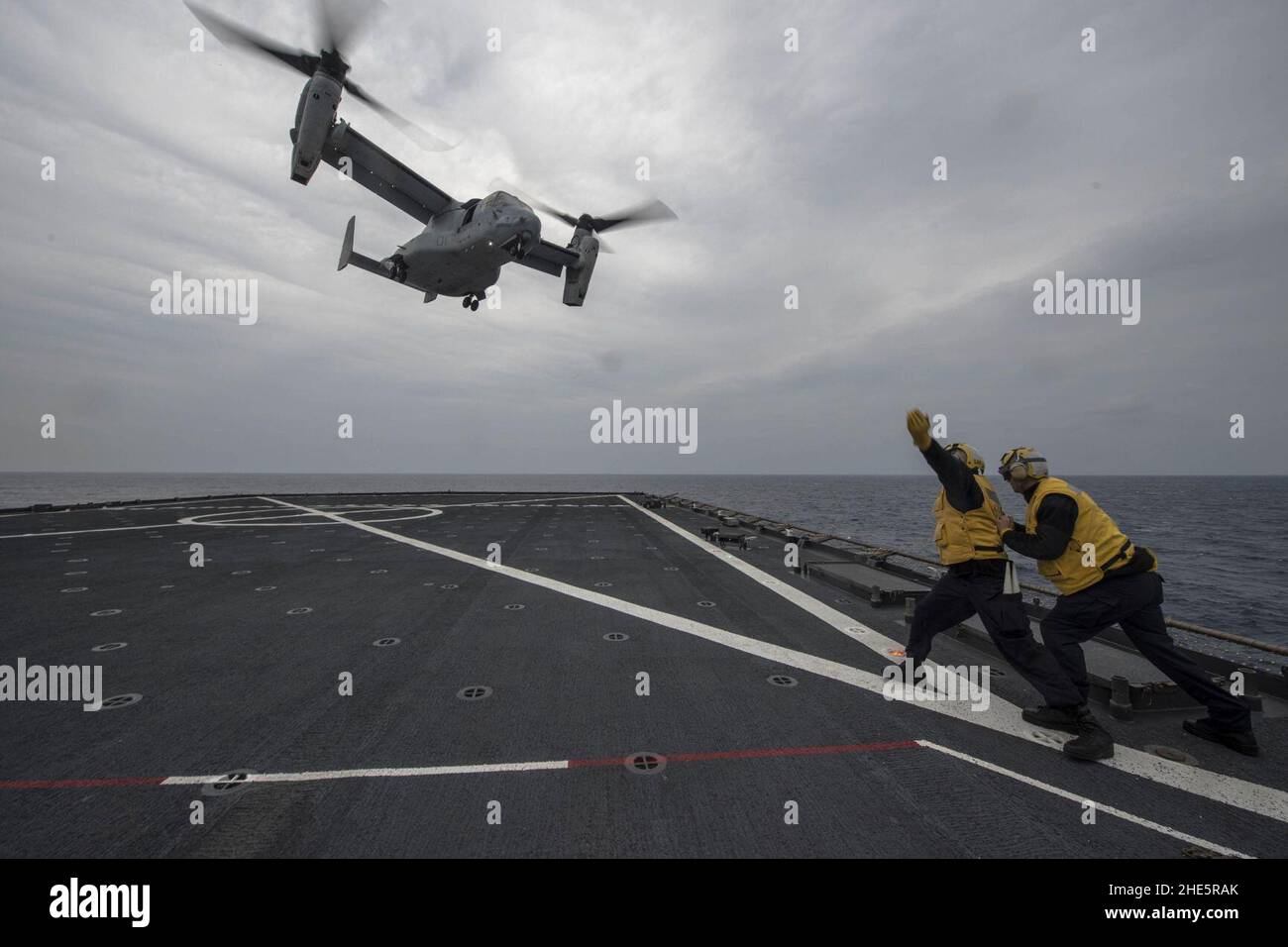 Sailors signal to an MV-22 Osprey during flight quarters aboard the USS ...