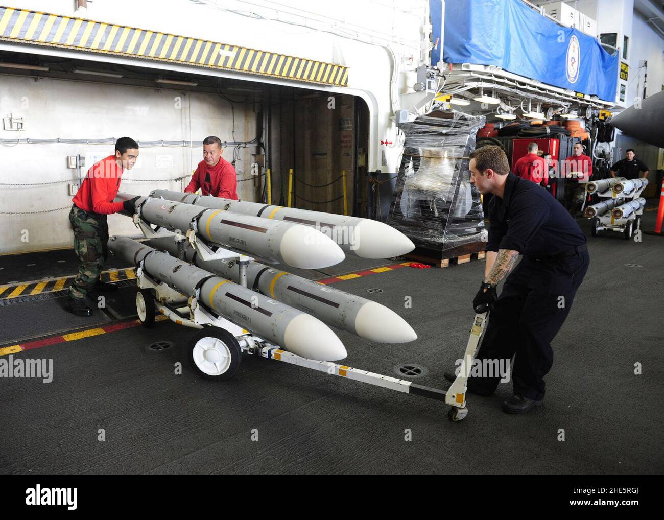 Sailors transport RIM-7P NATO sea sparrow missiles in the hangar bay of ...