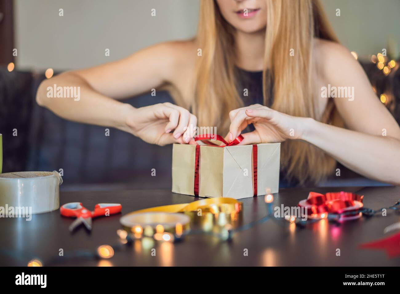 Young woman is packing presents. Present wrapped in craft paper with a ...