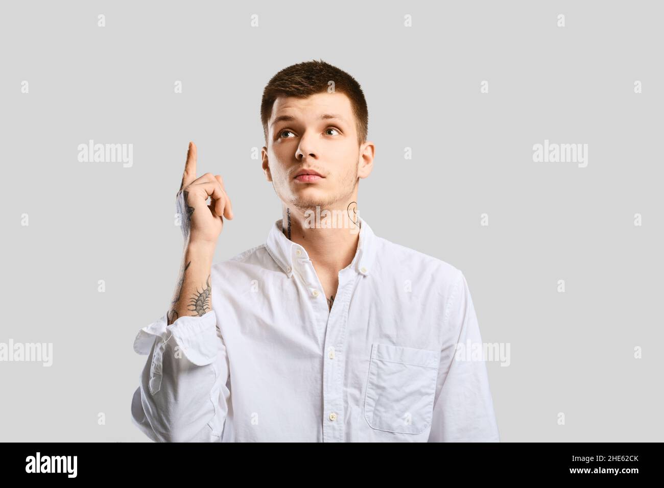 Young man pointing forefinger up over grey background Stock Photo - Alamy