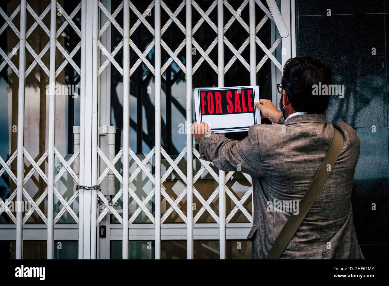 Back view of professional business man putting for sale box panel on ...