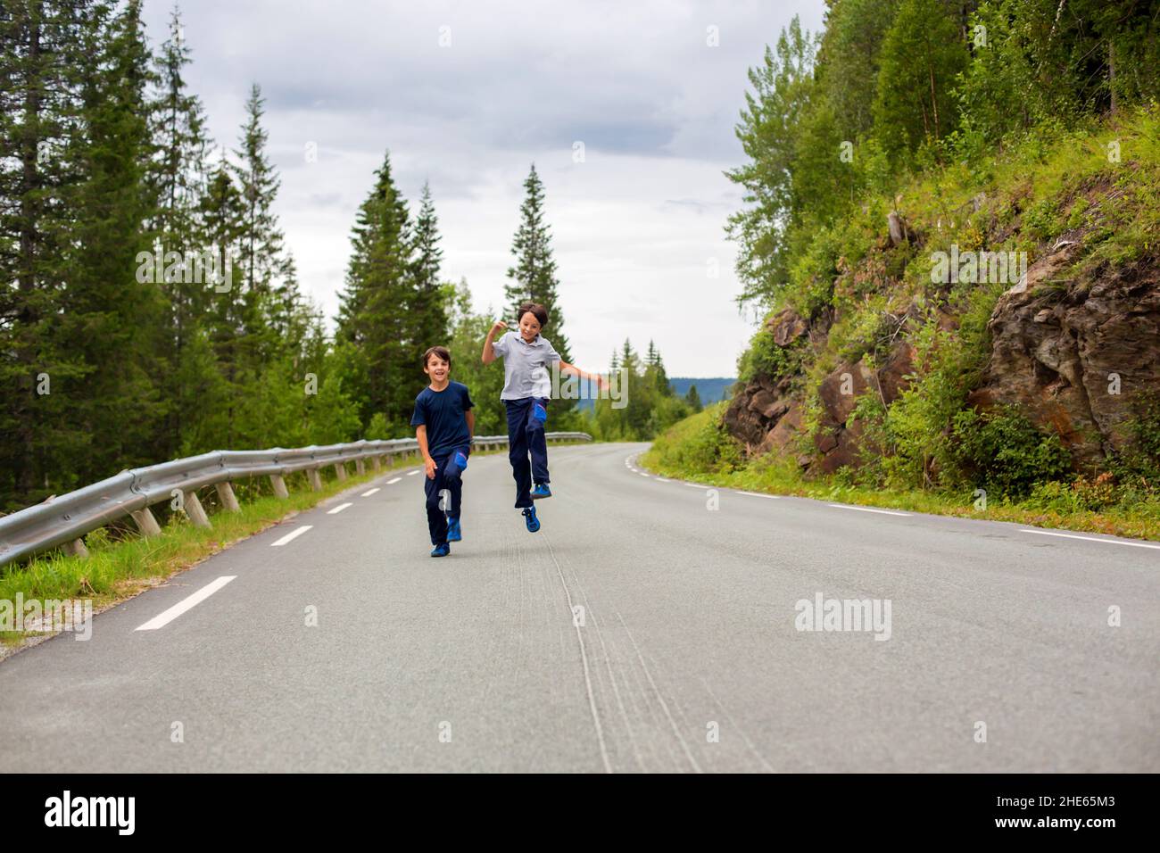Children, running on an empty road in Norway, beautiful nature around ...