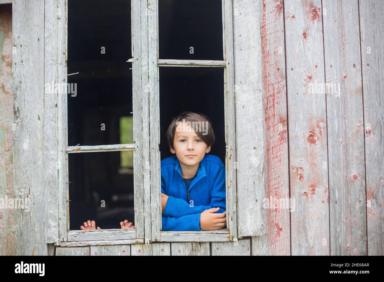 Sad child, looking out of the window of old an ruined building Stock ...