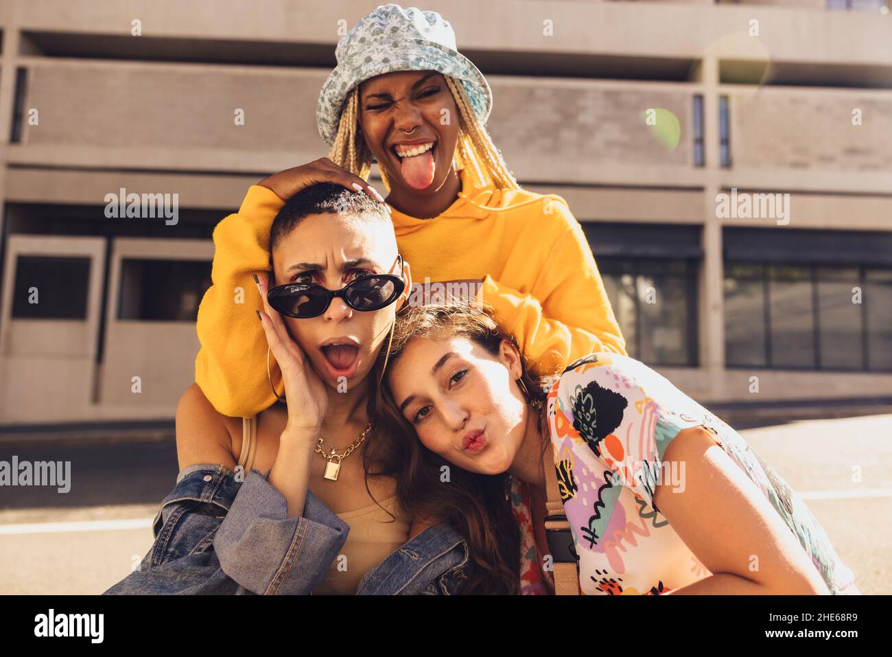 Three female friends having fun together outdoors. Trendy group of generation z friends making ...