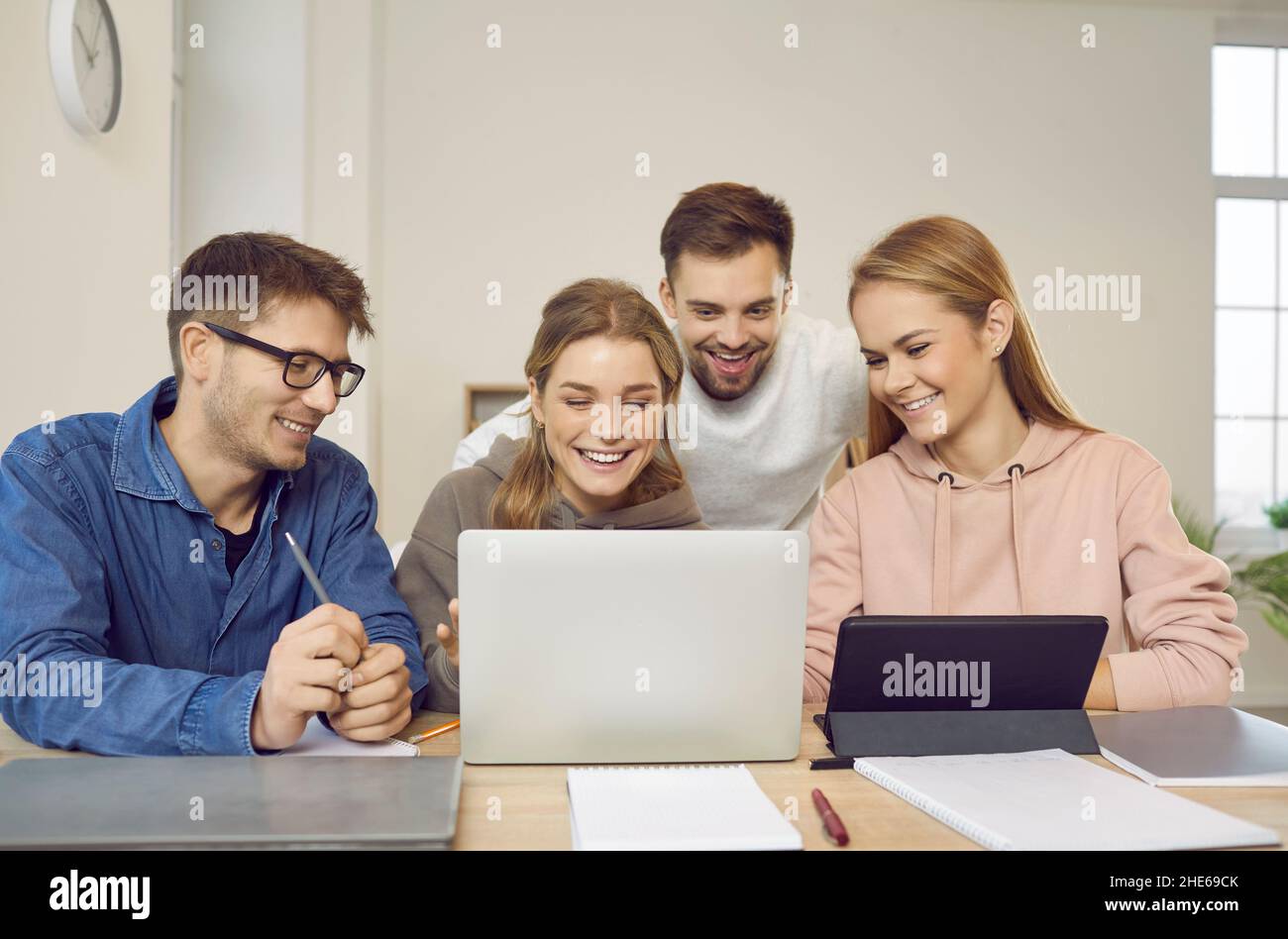 Group of happy university students using laptop while working on their ...