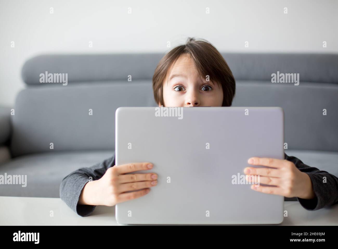 Preteen child, hiding behind notebook, online education, games and fun ...