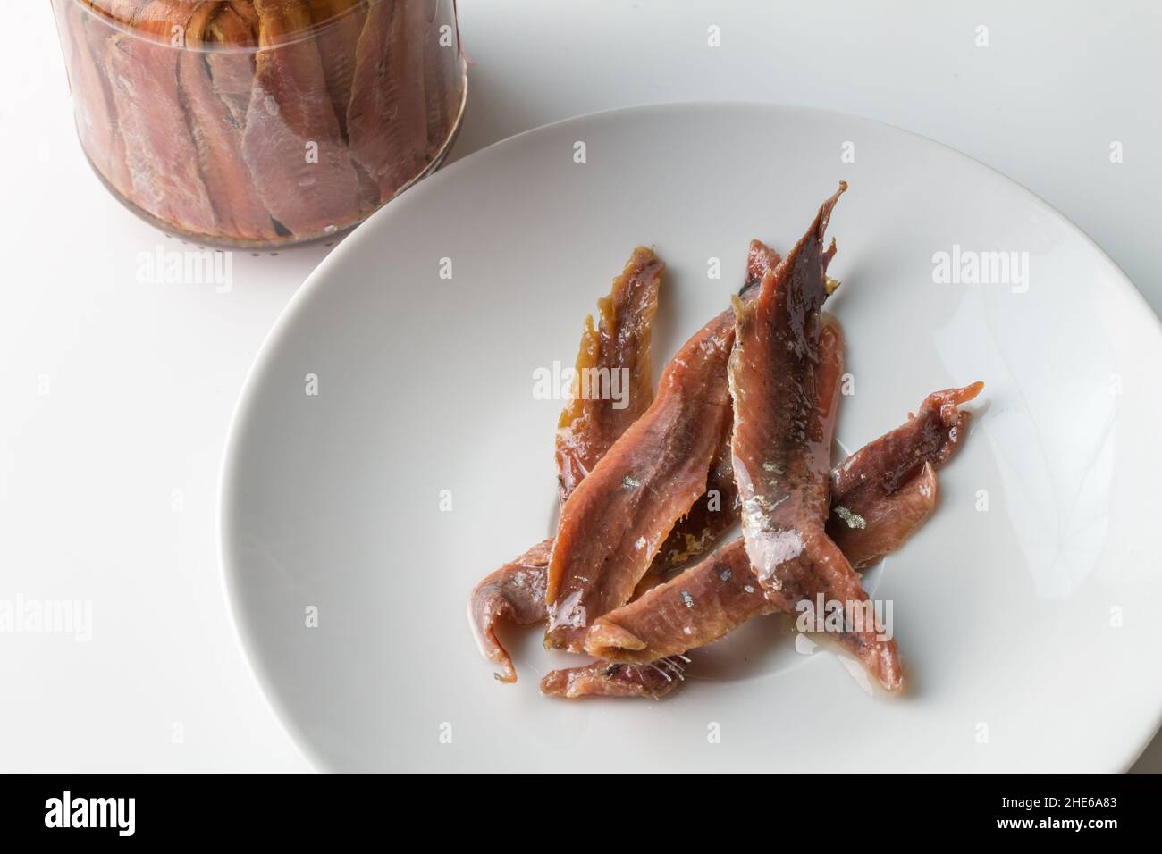 Preserved bottle anchovy fillets on white plate - anchovies on white ...