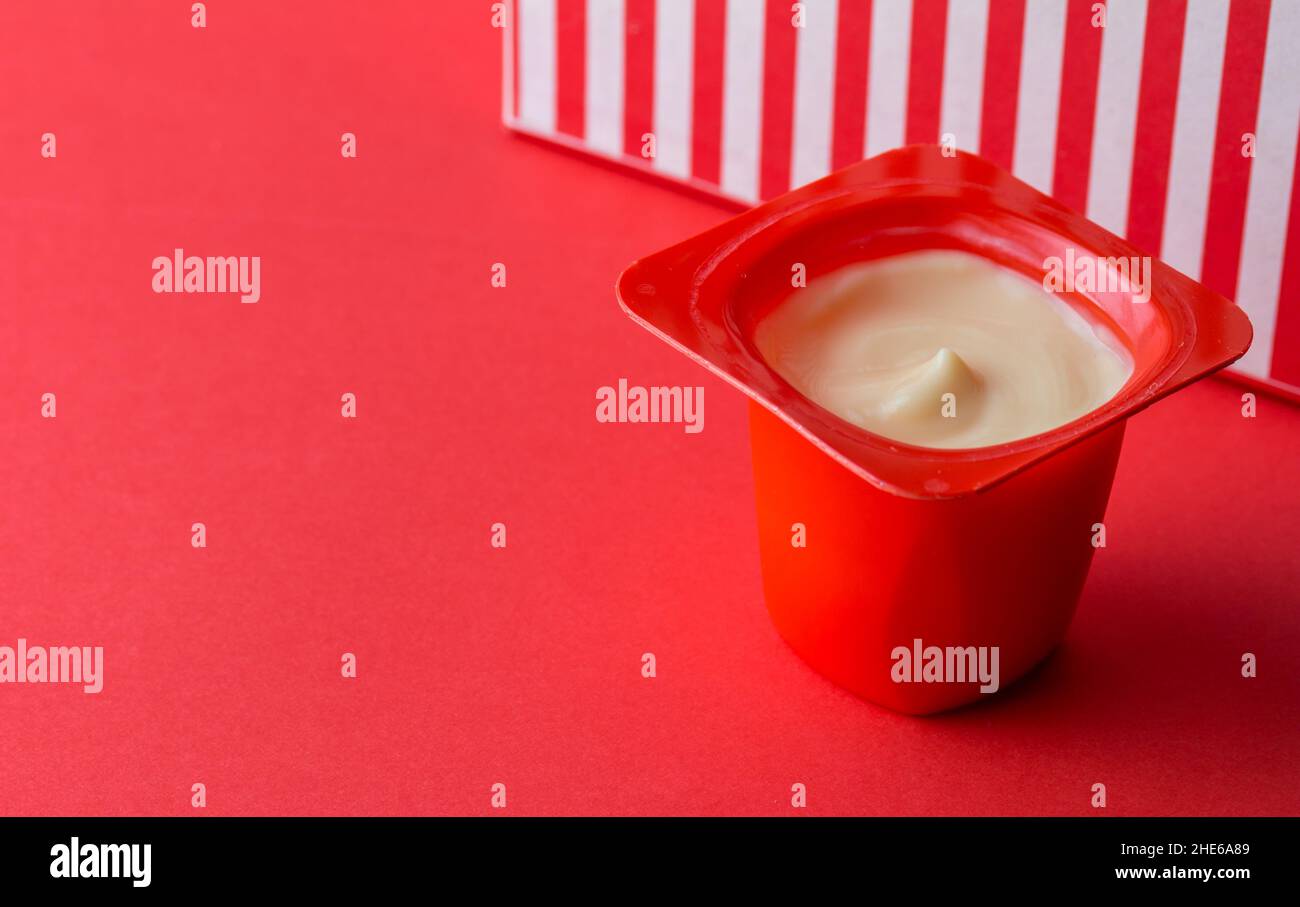 Small red yogurt container with fruit yoghurt isolated on fun red ...