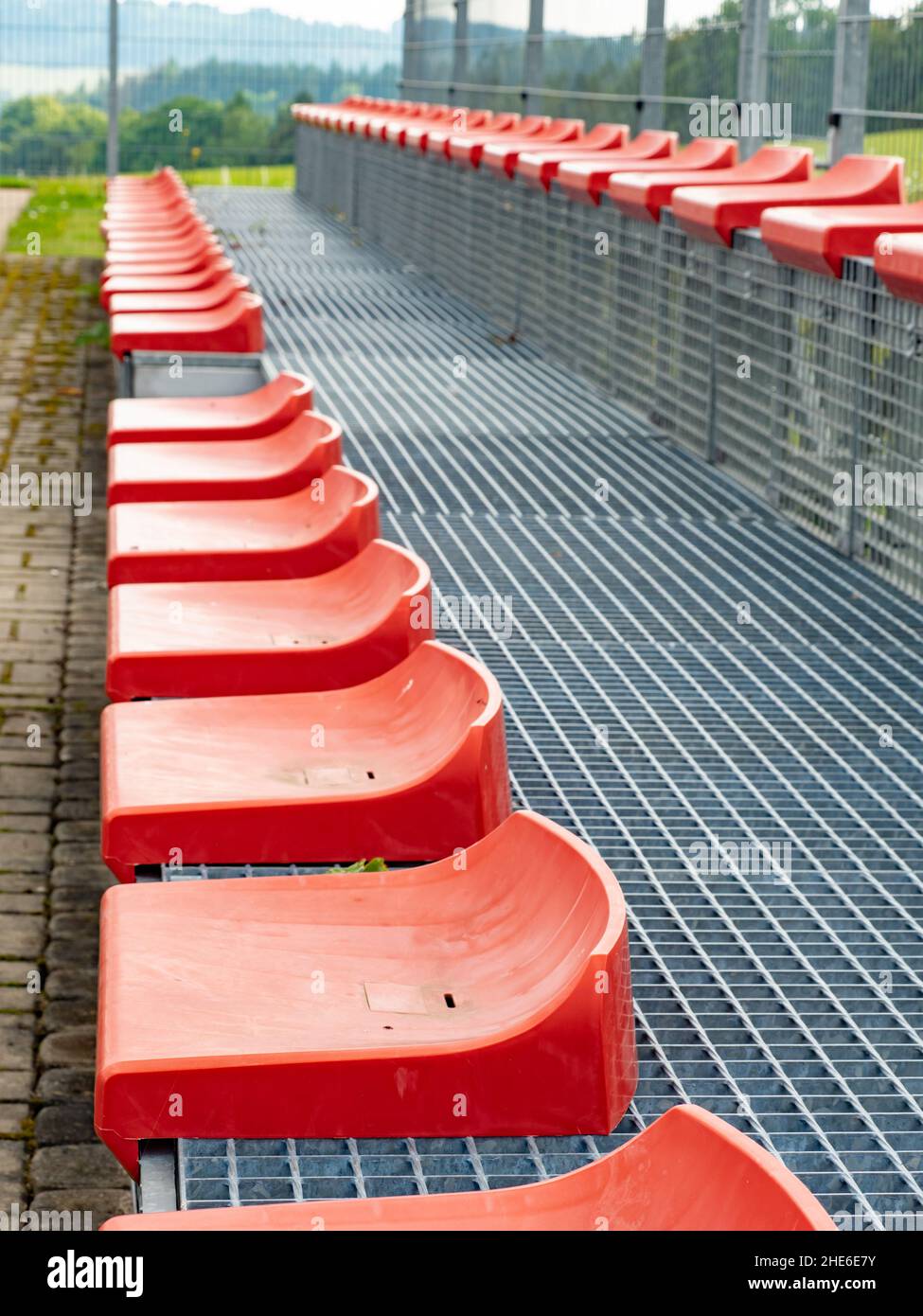 Cheap red stadium seats view. Two rows of simple chairs on tribune ...