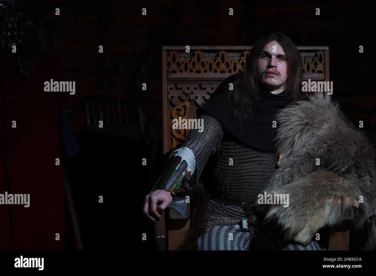 A mighty hero with long hair in chain mail armor in an ancient hall ...