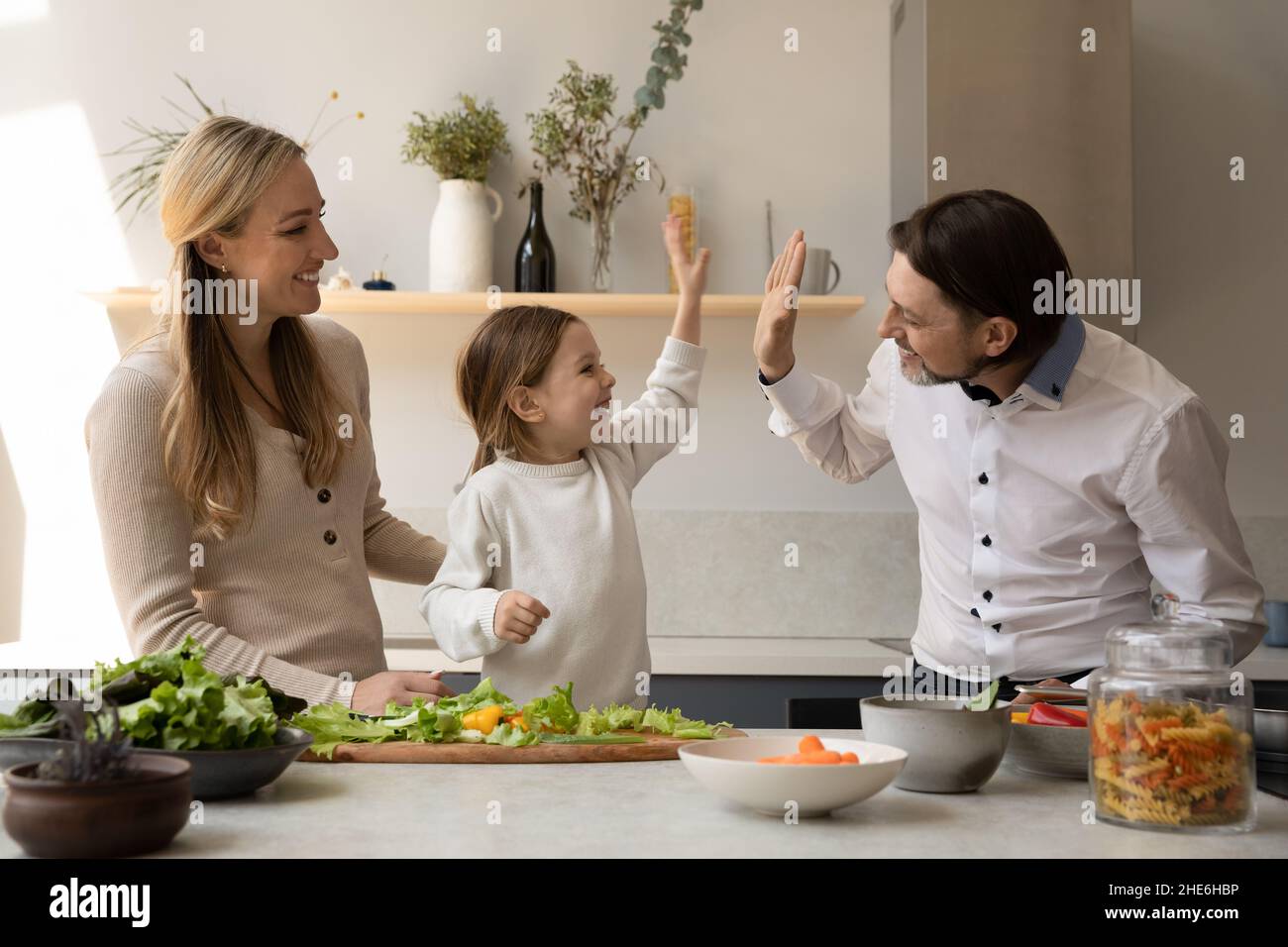 Excited cheerful daughter girl helping parents to cook dinner Stock ...