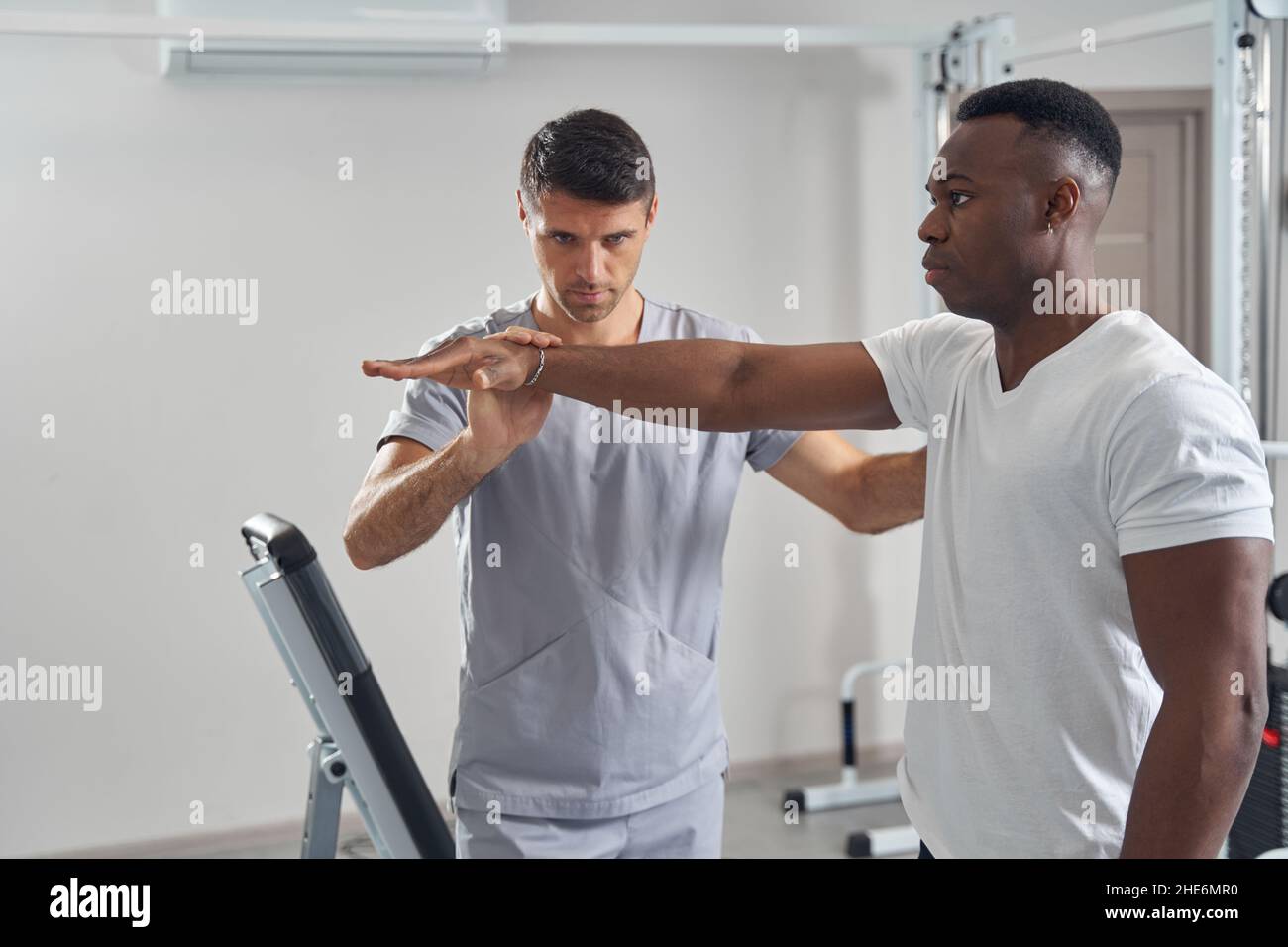 Concentrated physiotherapist performing resisted isometric test of ...