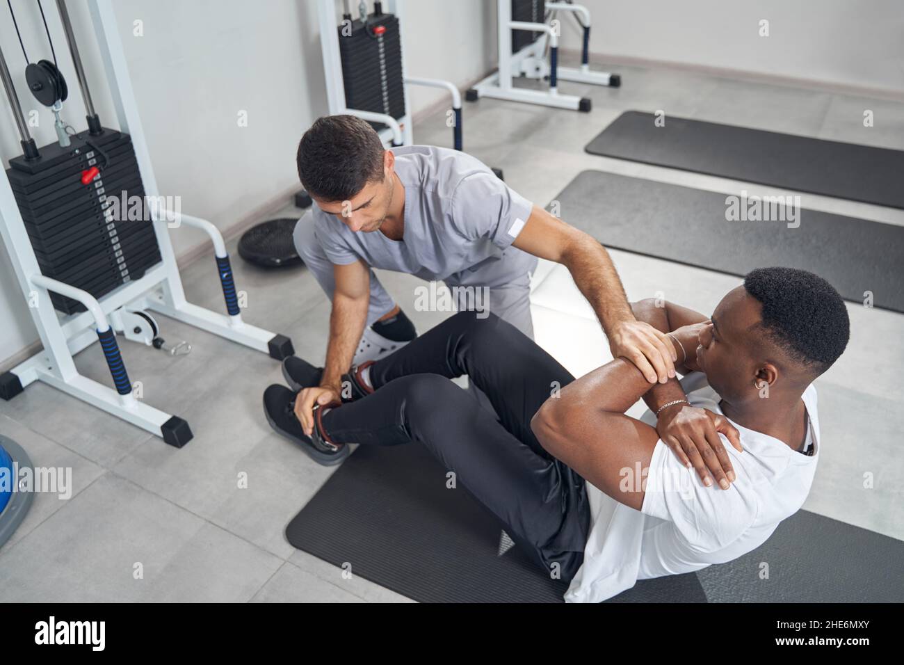 Physiotherapist assessing muscle strength of young man Stock Photo - Alamy