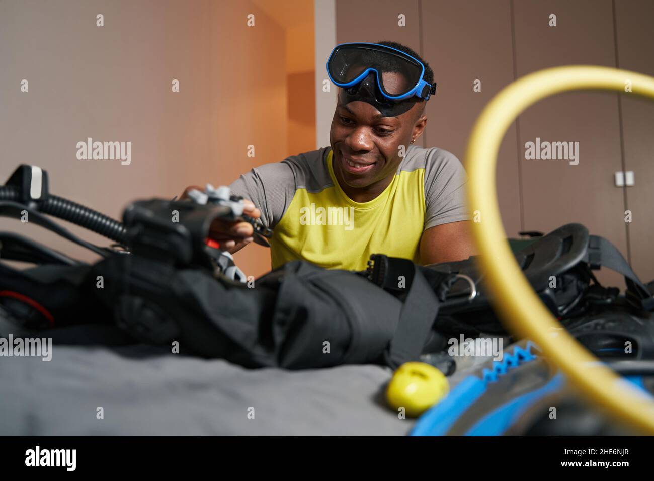 Happy multiethnic man lookiing at scuba diving suit on bed Stock Photo ...