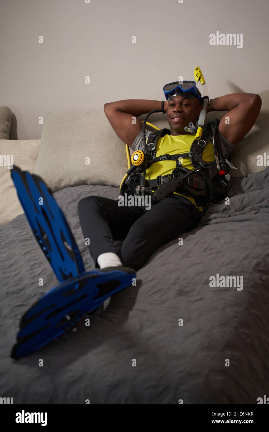 Man in scuba suit resting on bed Stock Photo - Alamy