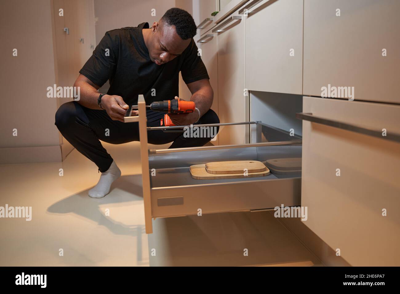 Diligent man screwing in drawer handle with drill Stock Photo - Alamy