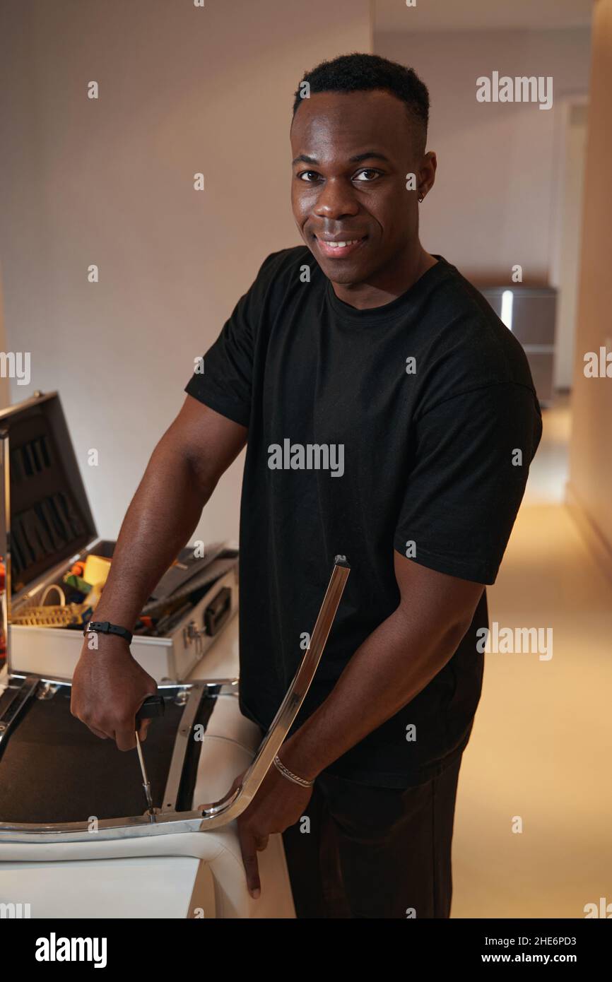 Multiracial man fixing chair with socket spanner Stock Photo - Alamy