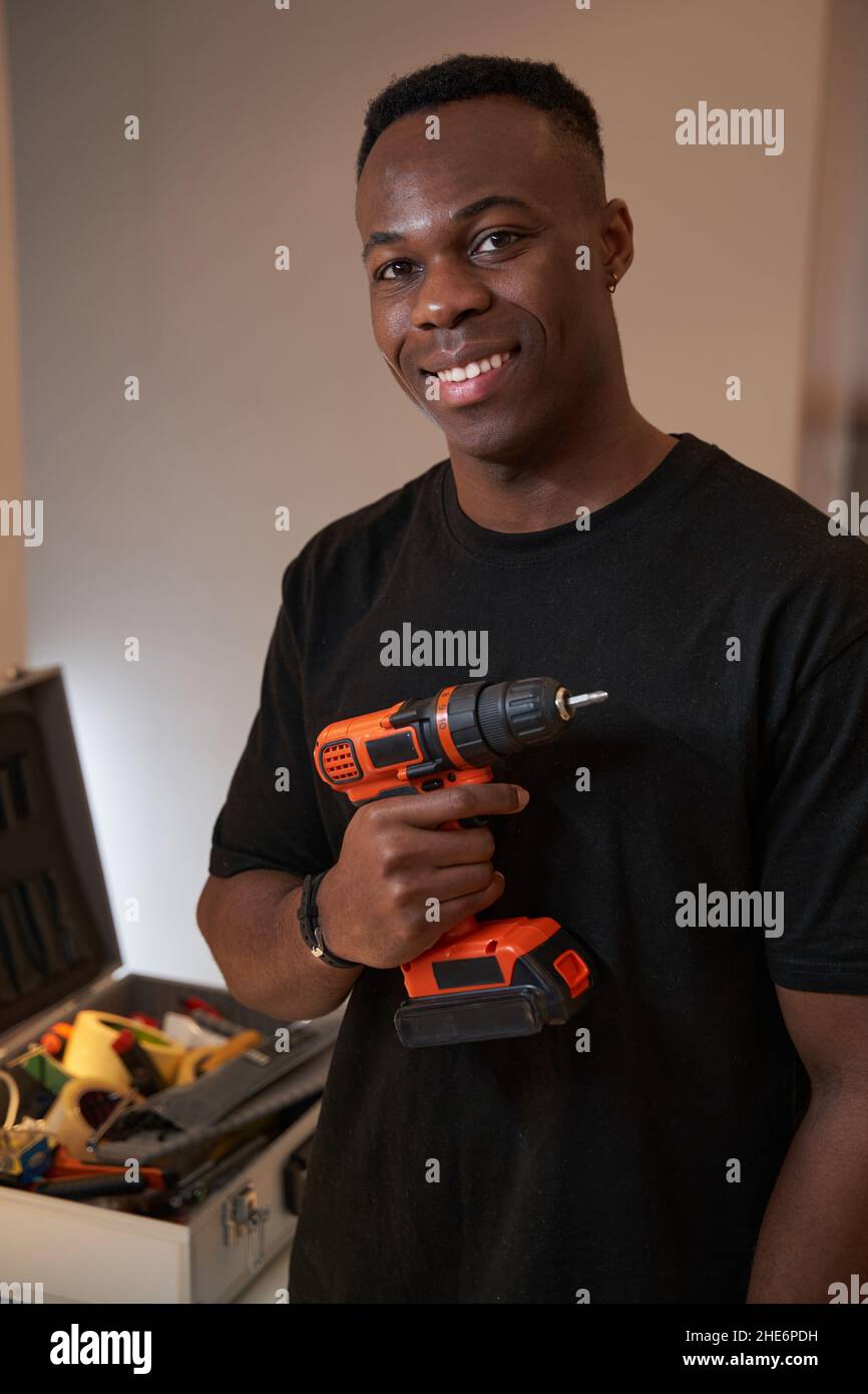Male smiling to camera while holding power drill Stock Photo - Alamy