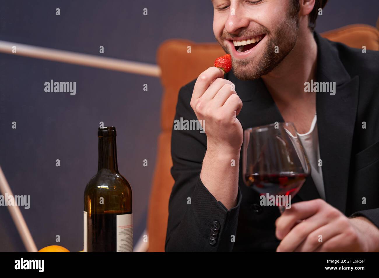 Happy man taking a bite from strawberry in restaurant Stock Photo - Alamy